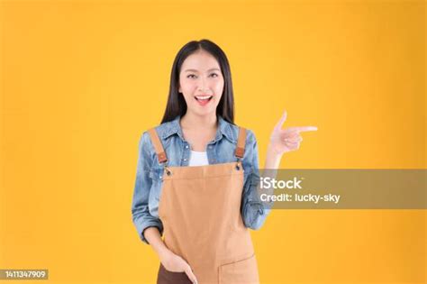 예쁜 아시아 여성 스마일 커피 프리랜서 자신의 커피 바 숍은 커피 종이 컵을 들고 자신의 상점 노란색 배경에서 신용 카드를 스 와이프하는 단말기 돈을 통해 신용 카드로