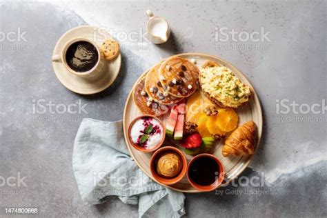 토스트 빵 계란 소스 크루아상 파인애플 딸기 에스프레소 커피 및 쿠키가 포함 된 전통 프랑스 식 아침 식사는 아랍 식 아침 식사의 테이블 상단보기에 격리 된 접시에