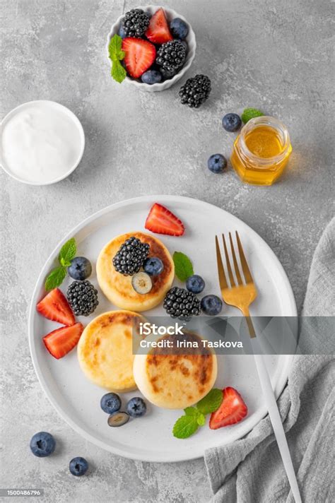 코티지 치즈 팬케이크 시르니키 신선한 딸기 꿀 사워 크림을 곁들인 리코타 튀김이 회색 콘크리트 배경에 있습니다 건강하고 맛있는