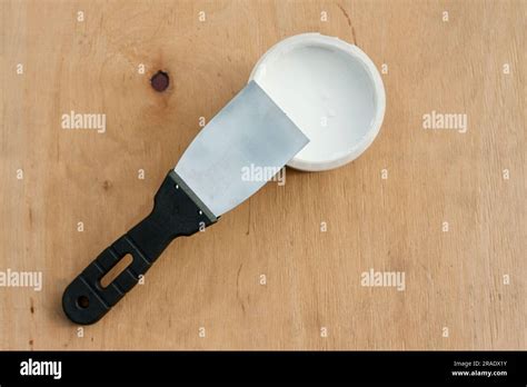 Construction Putty Knife And Can Of White Putty On Plywood Surface Still Life Putty