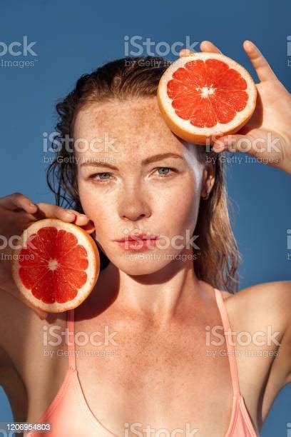 여름 자유형 주근깨와 젖은 머리를 가진 젊은 여자는 자몽 반쪽 펜션과 함께 파란색 포즈에 고립 된 서 감귤류 과일에 대한 스톡