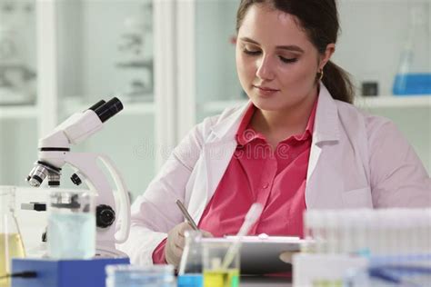 Female Scientist Taking Notes While Reviewing Results Of Scientific Experiments In Laboratory