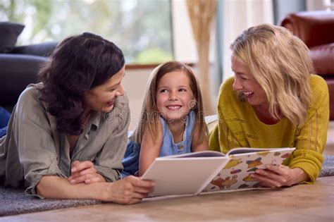 Familia Del Mismo Sexo Con Dos Madres Maduras E Hija Tumbadas En El Suelo Leyendo El Libro