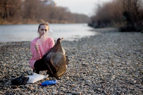 Premium Photo Young Female Volunteer Collecting Garbage On The River