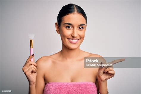 젊은 아름 다운 갈색 머리 여자 착용 수건 후 샤워 적용 화장품 을 사용하여 주걱 매우 행복 가리키는 손과 손가락 옆 가리키기에