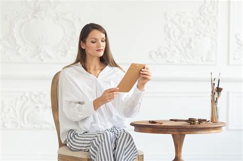 고급스러운 인테리어의 한 어린 아름다운 소녀가 의자에 앉아 손에 편지를 들고 읽습니다 소프트 포커스 엽서에 대한 스톡 사진 및 기타 이미지 Istock