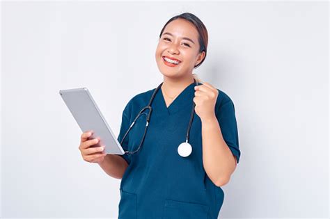 파란색 유니폼을 입고 일하는 젊은 아시아 여성 간호사가 디지털 태블릿을 들고 흰색 배경에 고립되어 성공을 축하하는 모습을 보여주고 있다 의료 의학 개념 25 29세에 대한