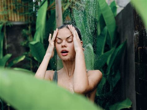 A Woman Takes A Shower And Washes Her Head And Hair Outdoors Against