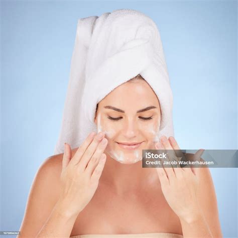 샤워 여자 스튜디오에서 거품으로 얼굴을 씻고 파란색 배경과 화장품을 청소합니다 행복한 여성 모델 얼굴 스킨케어 및 비누로 건강한 미적 광채 피부과 또는 보습 미용 25 29