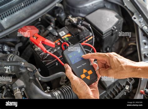 Close Up Hands Of A Male Auto Mechanic Using A Battery Tester To Check On The Car Battery Status