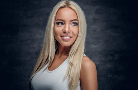 Спортивная блондинка в белой футболке на сером фоне Бесплатно Фото
