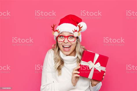 흰색 따뜻한 스웨터와 빨간 산타 모자를 쓴 한 젊은 여성이 흰색 리본과 리본이 달린 선물 상자를 보여줍니다 크리스마스와 새해 컨셉 여자에 대한 스톡 사진 및 기타 이미지