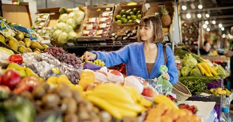 현지 시장에서 신선한 과일을 고르는 젊은 쾌활한 여자 재사용 가능한 메쉬 가방으로 쇼핑 지속 가능성과 유기농 현지 음식 개념