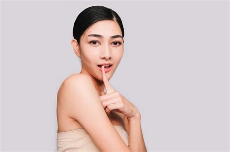 깨끗하고 밝은 피부와 젊은 아름다운 아시아 여자 화장품 뷰티 개념 손이 뺨에 터치 회색 배경에 고립 미소와 친절한 얼굴 건강