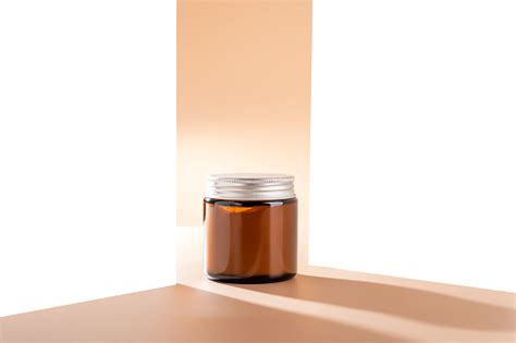 어두운 유리 항아리에 얼굴 크림은 베이지색 배경에 단단한 그림자가 있는 금속 뚜껑이 있습니다 트렌디한 카탈로그 이미지 얼굴 및