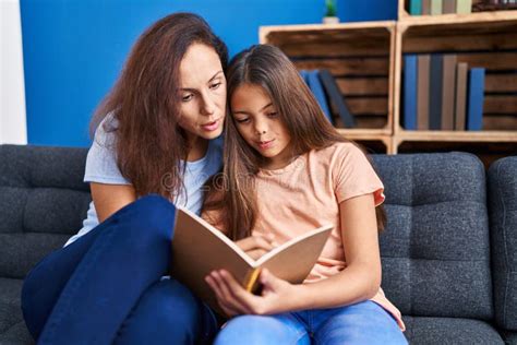 Woman And Girl Mother And Daughter Reading Book At Home Stock Image