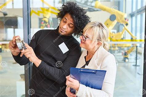 Engineers Discussing Robotics Component In Industrial Setting With