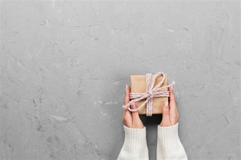 여자 손에 빨간 리본으로 종이에 포장된 발렌타인 또는 다른 휴일 수 제 선물을 제공합니다 선물 상자 흰색 시멘트 테이블에 선물 복사 공간 평면도의 장식 공예에 대한 스톡