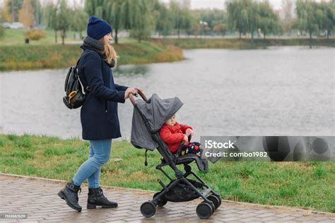 호수 근처에 유모차와 작은 아이가 있는 한 여성이 공원에서 산책을 합니다 가족에 대한 스톡 사진 및 기타 이미지 가족