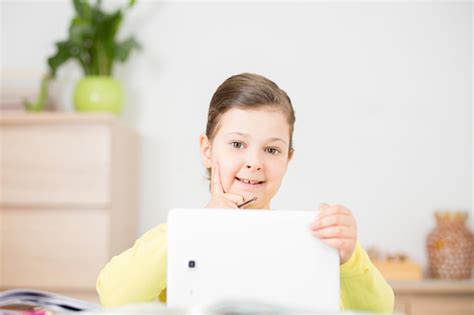 원격 학습 온라인 교육 집에서 공부 수업을 흰색 디지털 태블릿과 미소 여학생 소녀 격리 자기 고립 시 학교 교육 및 사회적 거리의 온라인 개념 가정 생활에 대한 스톡 사진