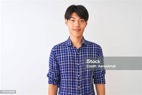 얼굴에 행복하고 시원한 미소와 고립 된 흰색 배경 위에 서 캐주얼 블루 셔츠를 입고 젊은 중국 남자 운이 좋은 사람 긍정적인