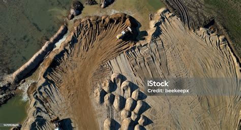 노천 모래 광산의 아리알 전망 프론트 로더는 더미에서 모래를 적재합니다 채석장에서 일하는 무거운 광산 기계 많은 바퀴 트랙과 사막 모래 언덕이나 가슴과 같은 모래 더미 건조