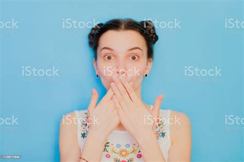 블루 스튜디오 배경에 재미 귀여운 소녀 밝은 감정적인 여성 초상화입니다 손으로 입을 덮고 있는 여자 악의 3 원숭이 개념을