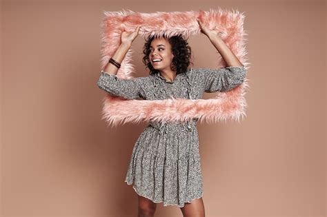 갈색 배경에 서서 푹신한 프레임을 들여다 보는 아름다운 아프리카 여성 갈색에 대한 스톡 사진 및 기타 이미지 갈색 개성 개념 다중 색상 Istock