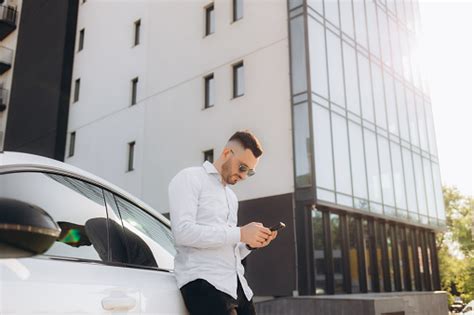 야외에서 현대 자동차 근처에 스마트폰을 가진 잘생긴 젊은 남자 30 34세에 대한 스톡 사진 및 기타 이미지 30 34세 Brand Name Smart Phone