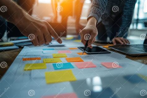 Collaborative Brainstorming Session With Sticky Notes And Hands Pointing At Project Plans Stock