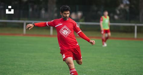 빨간 축구 유니폼을 입은 남자가 낮 동안 푸른 잔디밭에서 축구공을 차고 있다 사진 Unsplash의 무료 빨강 이미지
