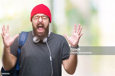 미친 미친 무기와 성공을 위한 축 하 하는 고립 된 배경 위에 빨간 모직 모자와 배낭을 입고 젊은 Hipster 남자 고 흥분 비명 눈을 폐쇄 우승자 개념 과체중에 대한