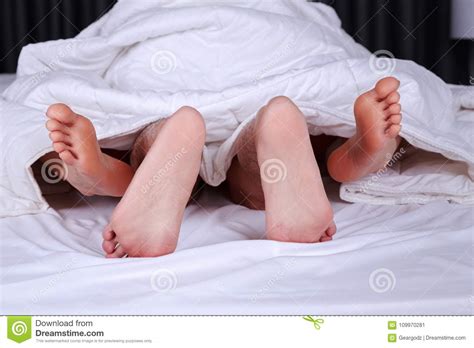 Couple Feet Seen From Under Blanket On Bed Stock Image Image Of