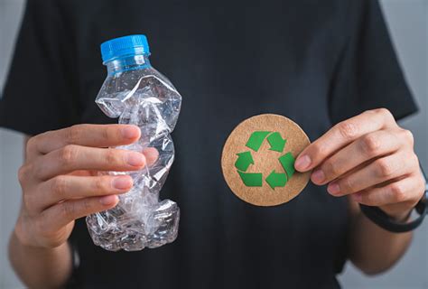 구겨진 플라스틱 물병과 공예 종이에 녹색 재활용 기호를 들고 있는 손 재활용 제품 및 환경 개념 개념에 대한 스톡 사진 및 기타 이미지 Istock