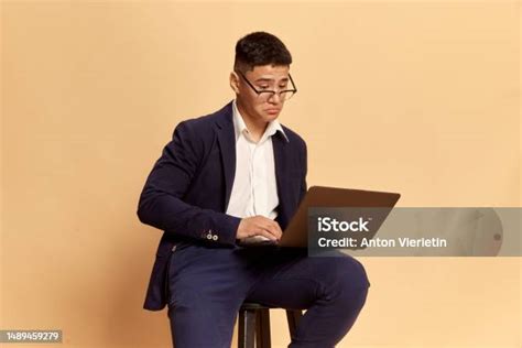 잘생긴 사업가 패션 스타일 의상을 입은 사무원 베이지색 배경 위에 화가 난 얼굴로 노트북 화면을 바라보는 정장 18 19세에 대한 스톡 사진 및 기타 이미지 Istock