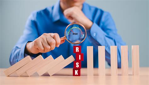 위험 관리 위기 개념 재무 분석 솔루션 부동산 사업 사업가는 돋보기를 사용하여 나무 블록 도미노 위기에 대한 경제적 위험 단어를 사용합니다 보험 보안 평가 금융에 대한 스톡