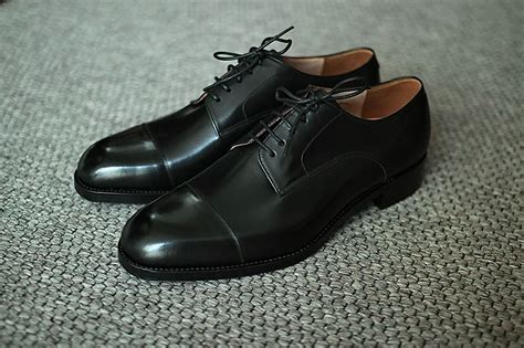 천안맞춤정장 굿 이에 웰트 제법으로 만들어진 검정색 구두입니다 더비 형태의 디자인이며 구두 끈이 꿰어지는 아일렛이 날개 모양의 구조물에 위치해 있습니다 발등이 닫혀