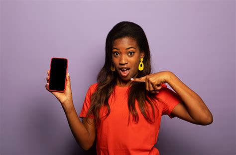 쾌활한 아프로 아메리칸 여성 프로모터 쇼 스마트폰 포인트 검지 손가락 선물 새로운 모던 디바이스 초상화 20 24세에 대한 스톡