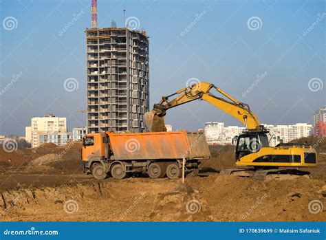 Загрузка экскаватора самосвалу на стройке в песок Экскаватор выкапывает землю для создания и