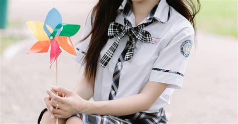 10대 검은 머리 공원 교복 긴 머리 낮 도시의 라이프스타일 레저 모델 미소 짓는 바람 부는 바람개비 배낭 소녀 앉아 있는 액세서리 야외 놀이