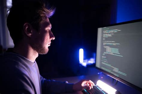 Premium Photo A Focused Male Developer Works On Programming Code On His Computer Screen In A