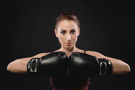 스포츠웨어와 복싱 장갑을 착용한 백인 여성 복서가 싸우는 자세로 카메라를 바라보고 있다 어두운 배경에 대해 강한 여자의 여자 싸움 건강한 생활방식에 대한 스톡 사진 및 기타