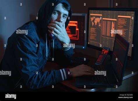 Male In The Hood Looking In The Camera Hacker Attacks And Online Fraud In The Dark On The