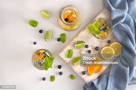 여름철 감귤류 주입된 물 레모네이드 또는 모히토 라임 레몬 오렌지 블루베리와 민트 다이어트 디톡스 음료 밝은 배경의 안경 감귤류