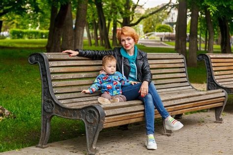 Hermosa Niña Madre Con Un Hijo En El Parque En El Parque Está Sentada En Un Banco Foto Premium