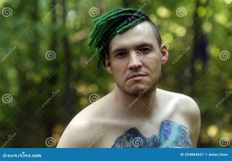 Young Naked Man With Green Dreadlocks Tattoo On Chest Posing In Forest