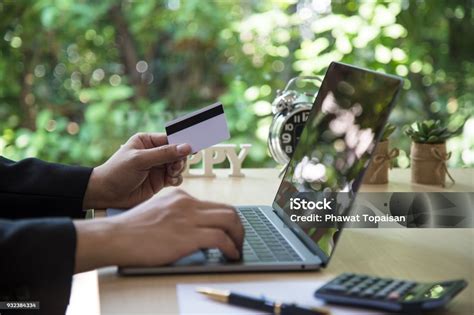 현대 사업 손 들고 펜 나무 테이블 소프트 포커스 플레어 태양 빛에 계산기와 함께 앉아있는 동안 컴퓨터 키보드에 숫자를 입력 하는 신용 카드의 후면 볼 수 있습니다 온라인