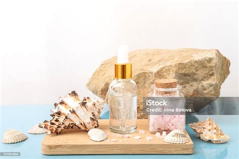 드롭퍼 투명 유리 화장품 병 모의 분홍색 바다 소금과 파란색 배경에 조개 친환경 케어 유기농 제품 뷰티 트리트먼트 스파 컨셉 공간을 복사합니다 건강한 생활방식에 대한 스톡