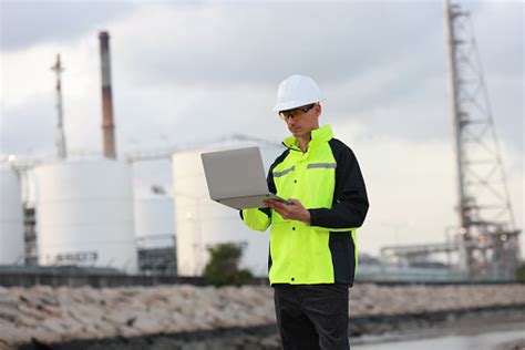 석유 및 가스 정유 플랜트 산업 공장 외부에서 검사관 안전 품질 관리를 위해 화학 물질 저장소에서 노트북으로 작업하는 석유 화학