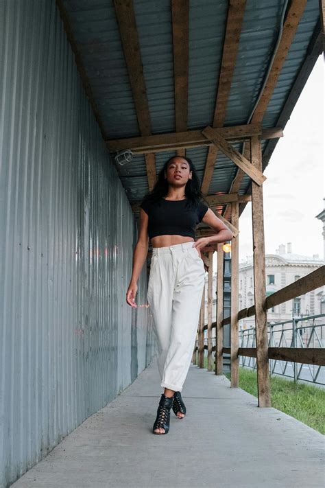 Woman In Black Shirt And White Pants Standing On Wooden Bridge · Free